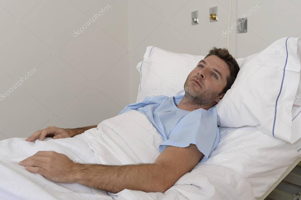 Young patient man lying at hospital bed resting tired looking sad and ...