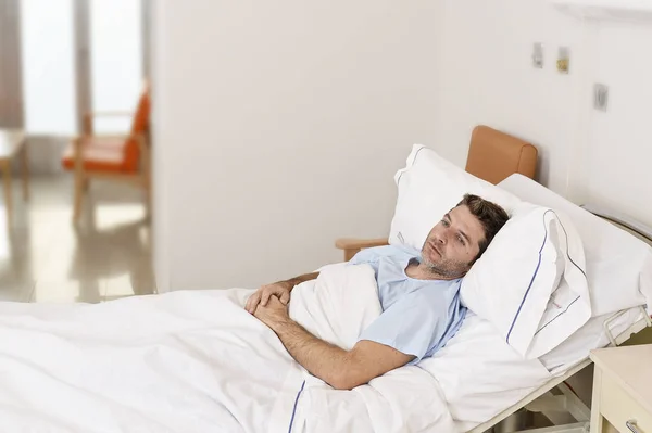 young patient man lying at hospital bed resting tired looking sad and ...