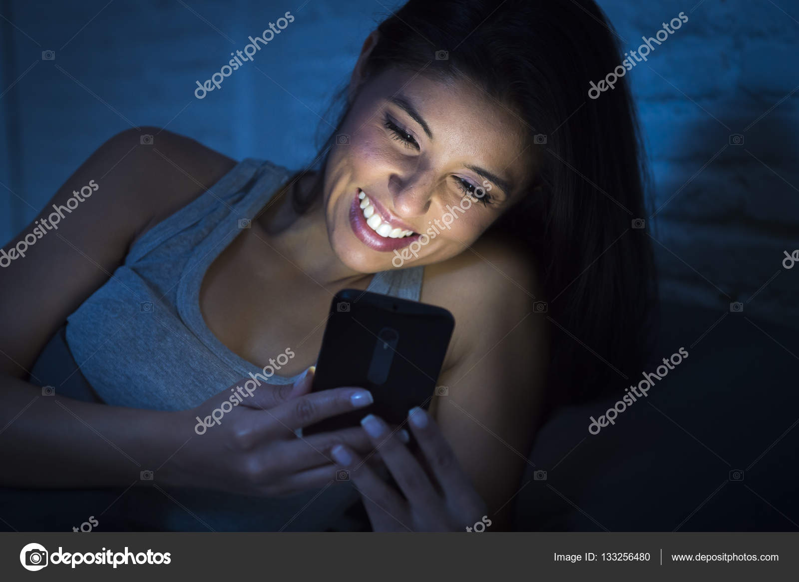 Girl in bed using mobile phone late at night at dark bedroom lying ...