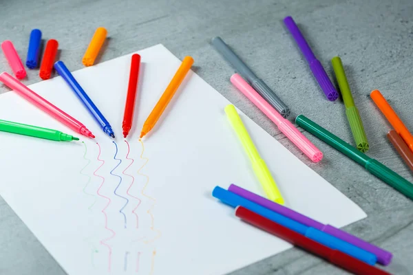 many multi-colored markers for drawing with drawings on white paper ...