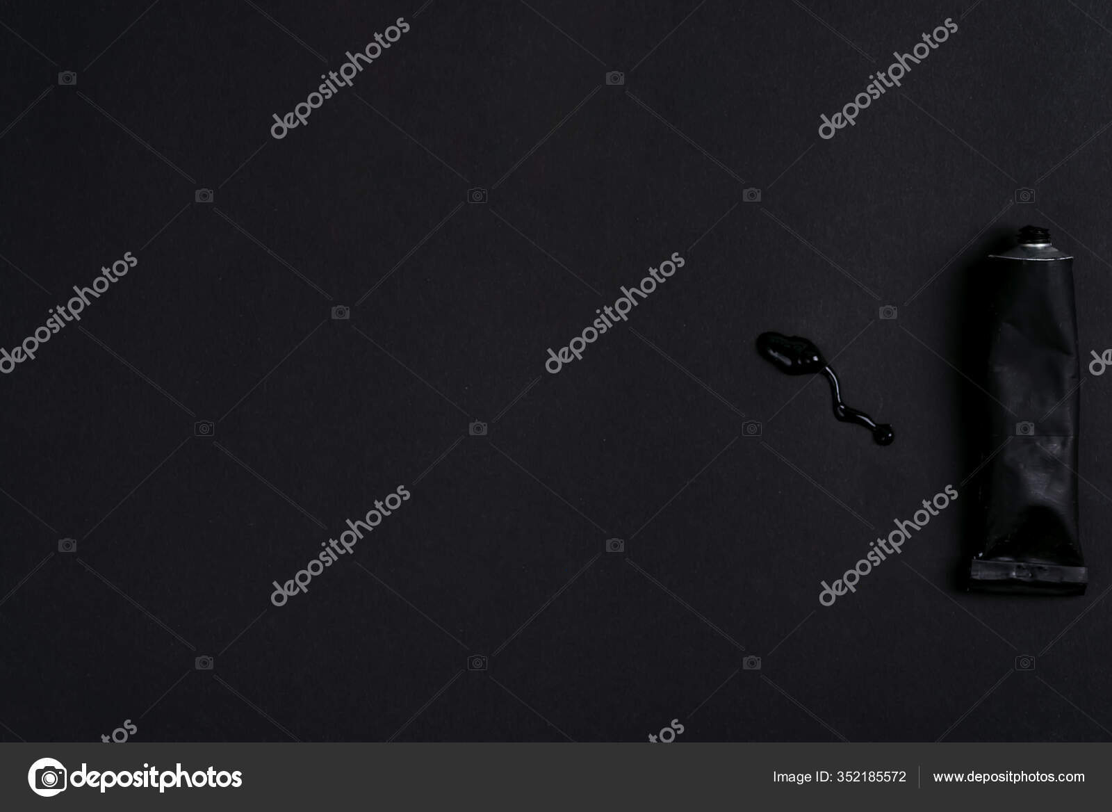 Black paint tin tube squeezed isolated on dark background. Top view ...