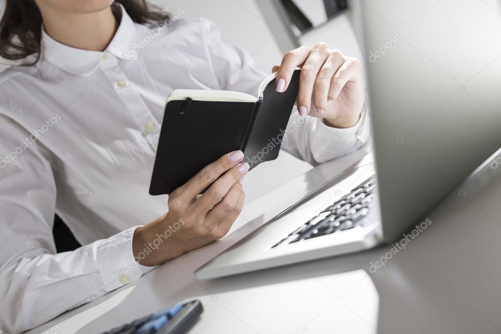 Close up of elegant woman's hands holding a tiny black notebook ...
