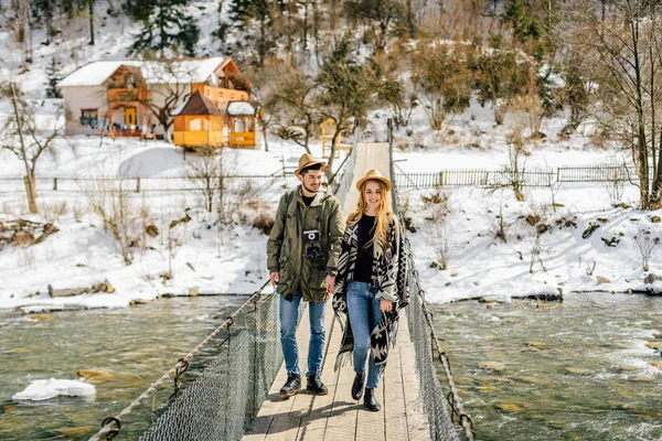 Couple of travelers overcome obstacle, mountain river in winter ...