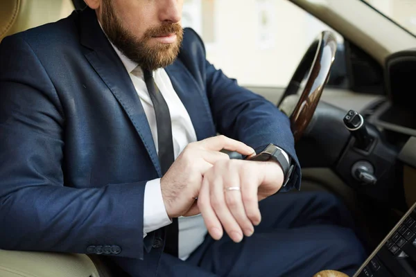 Close-up of man looking at watch while sitting in car hurrying to ...