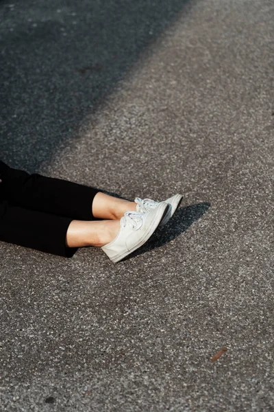 Legs in the black pants are stretched on a cobblestone floor in the ...