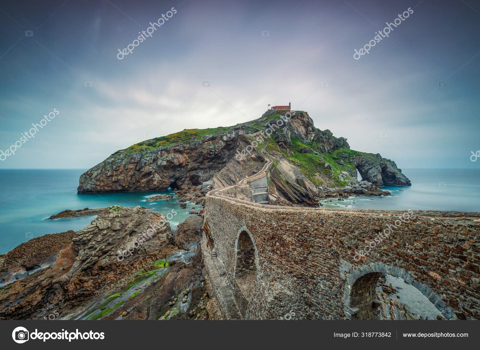 Old stone wall going over the ocean to an island — Stock Photo ...