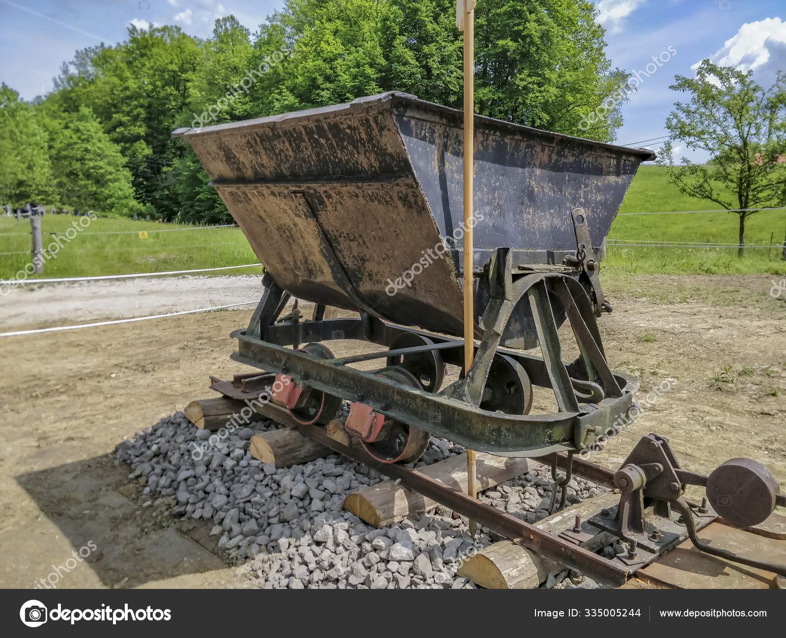 Old mine cart on tracks at daytime with a grassy field in the ...