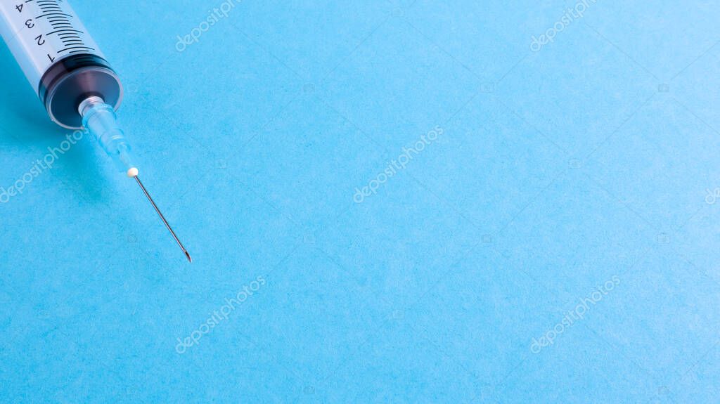 Sobre un fondo azul se encuentra una jeringa médica con una aguja ...