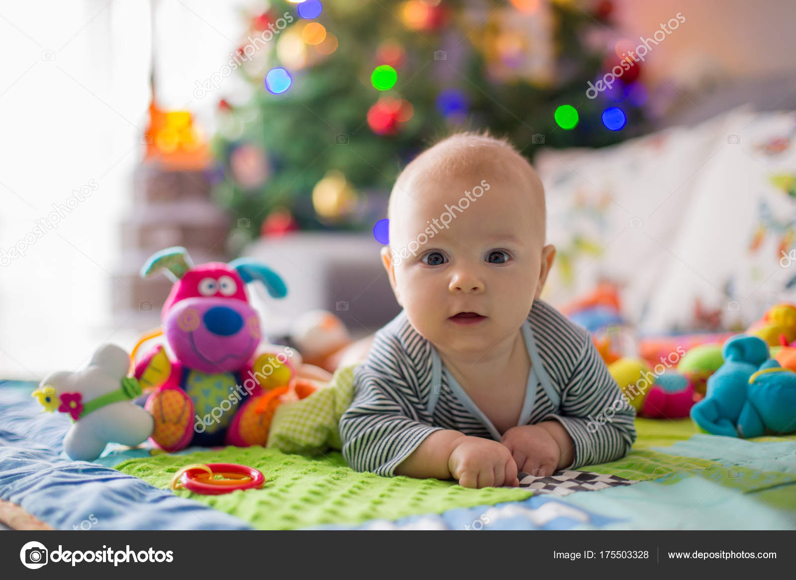 Happy three months old baby boy, playing at home on a colorful a ...
