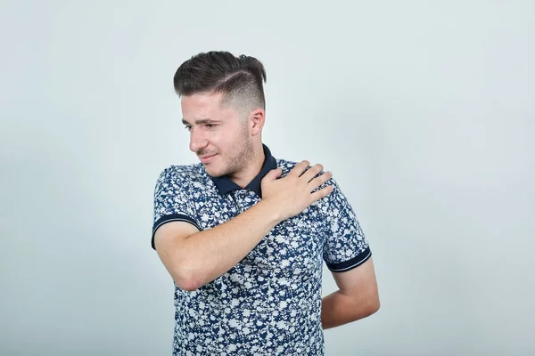 Handsome man keeping one hand on shoulder, other hand behind back ...