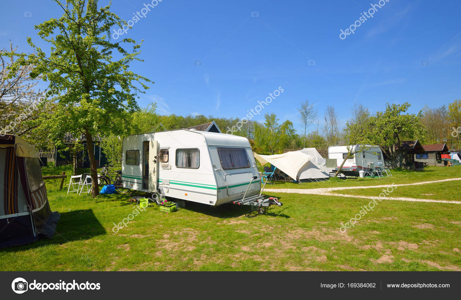 White caravan trailer on a green lawn in a camping site. Sunny day ...