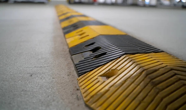 Traffic safety speed bump on an asphalt road in a parking area. Speed ...