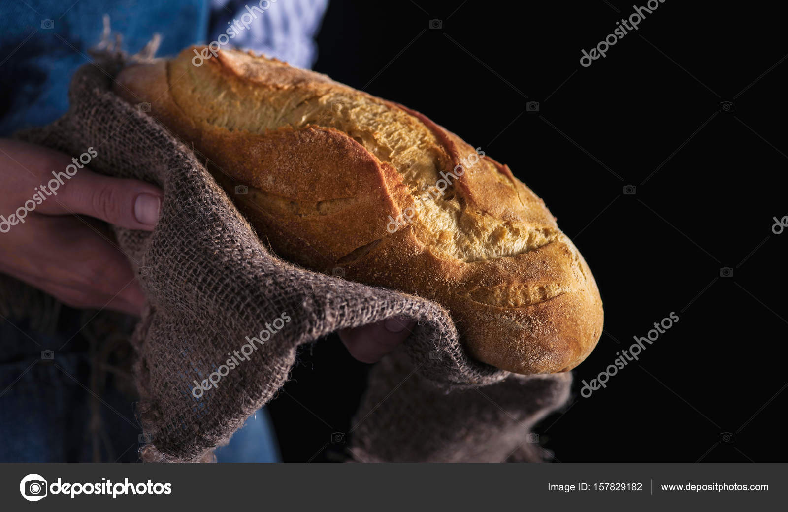 Baker's hands hold fresh bread over dark background Stock Photo by ...