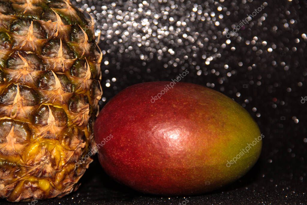 Piña con mango sobre un fondo negro brillante. Media piña y un mango ...