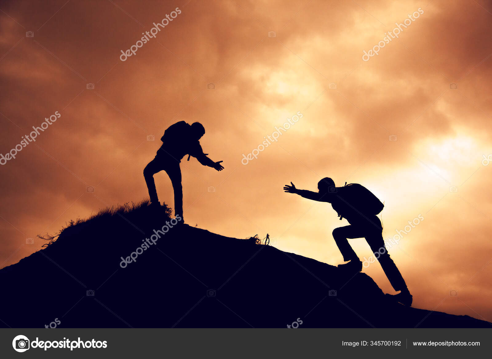 Two people help each other on top of a mountain climbing team Stock ...