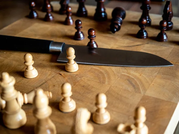 Chess pieces and kitchen knife. Strategy game. It is played on a 64 ...
