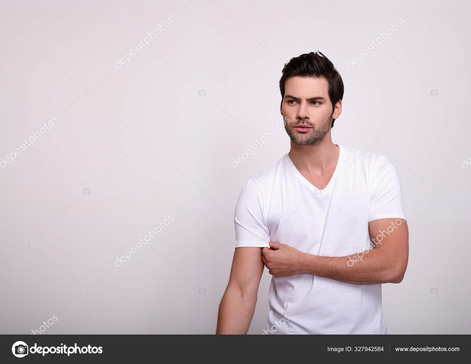A handsome male model in the studio on a white background looks to the ...