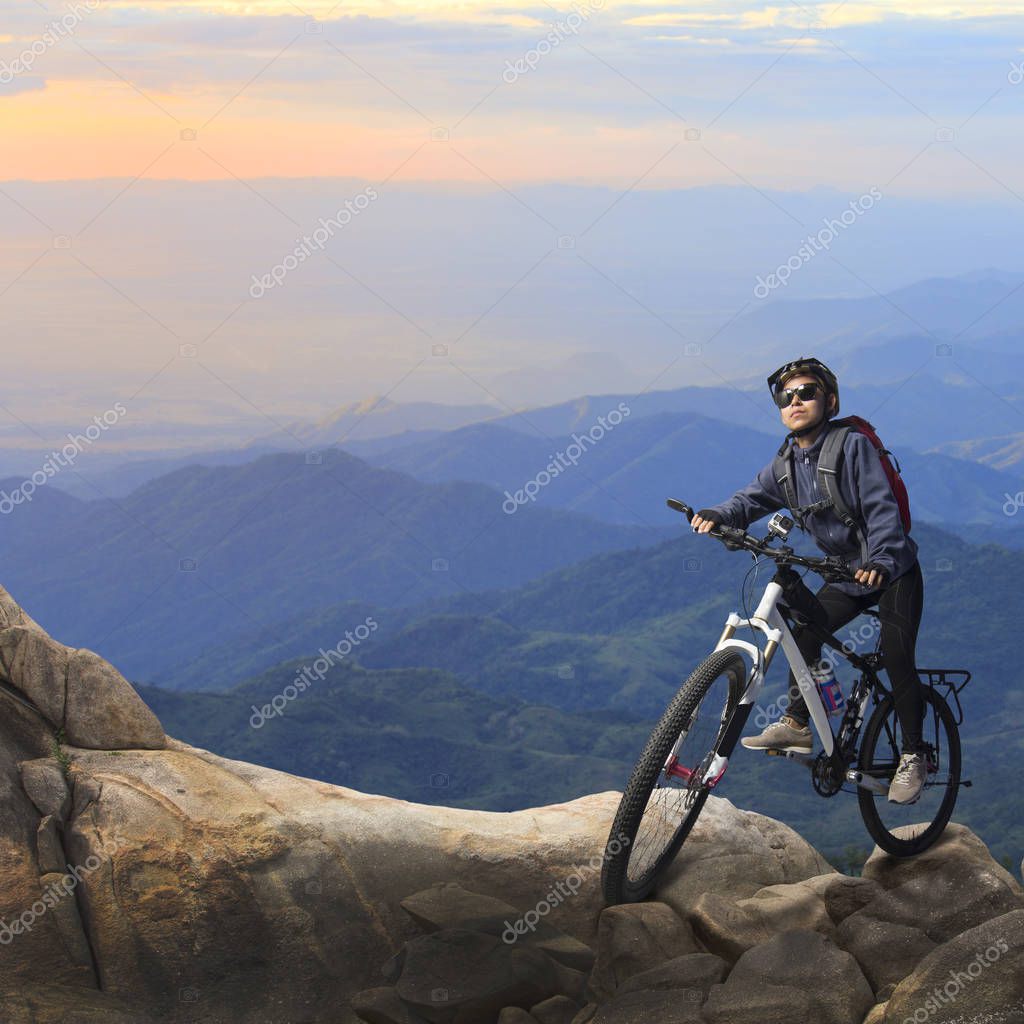 Велосипедист с рюкзаком на велосипеде на вершине скалистой горы ...