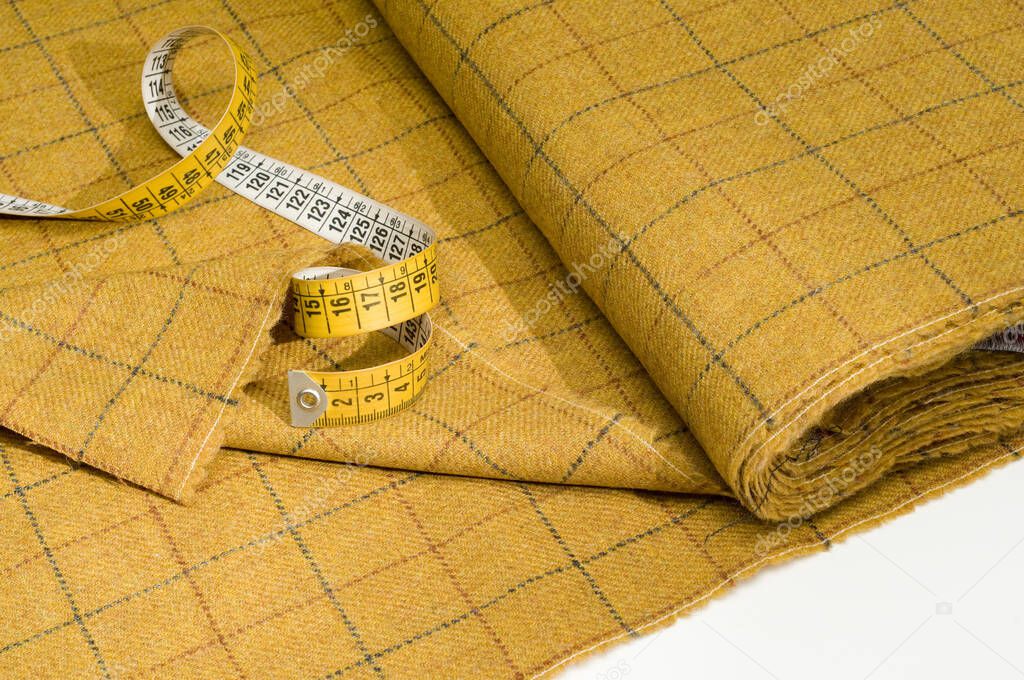 una pieza de tela, tijeras, medida de cinta y clavijas en la mesa del ...