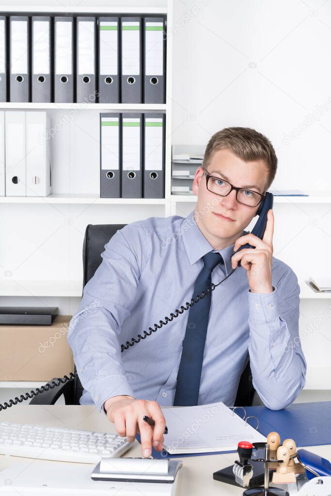 Joven hombre de negocios con gafas se sienta en su escritorio en la ...