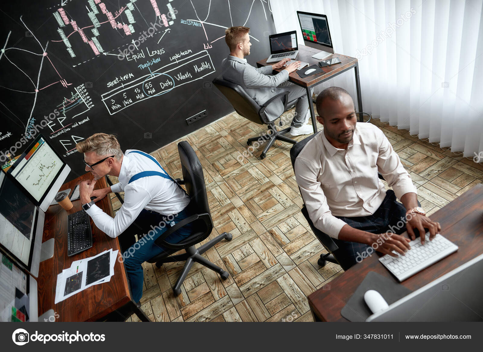 An unlimited way of learning. High-angle view of three traders sitting ...
