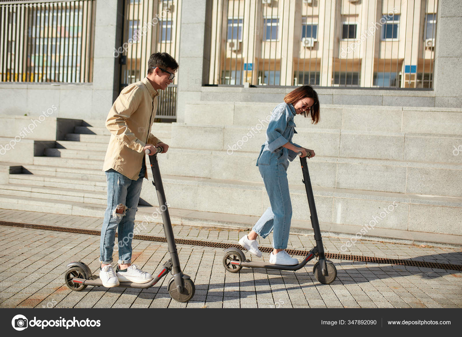 Enjoy your ride. Two friends having fun driving electric scooters on a ...