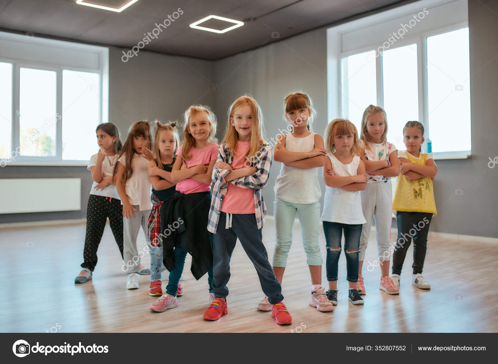Cute dancers. Group of positive little girls keeping arms crossed and ...