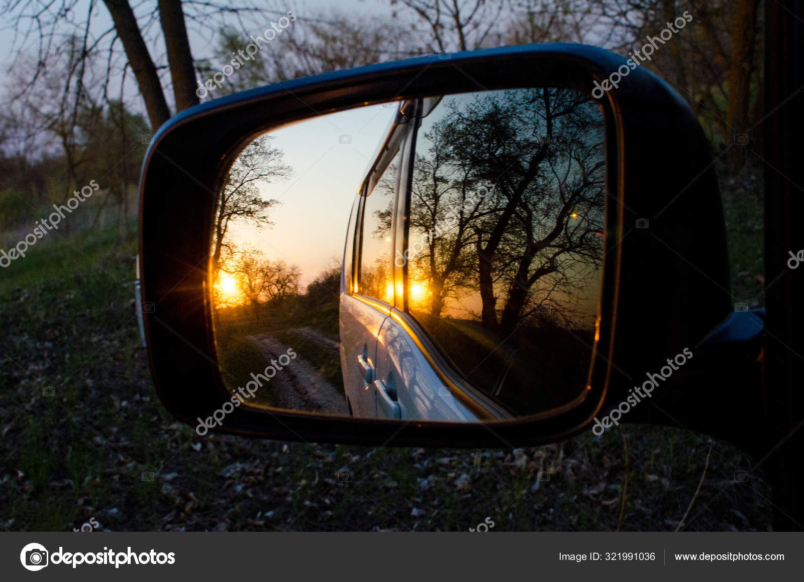 Side rearview mirror of car with reflection of beautiful sunset in the ...