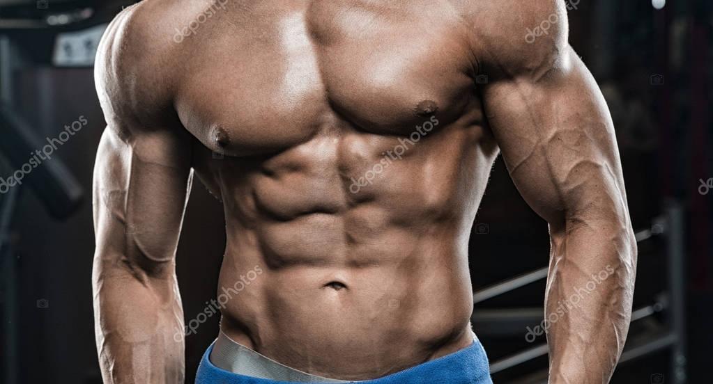 Hombre guapo con grandes músculos, posando en la cámara en el gimnasio 2023
