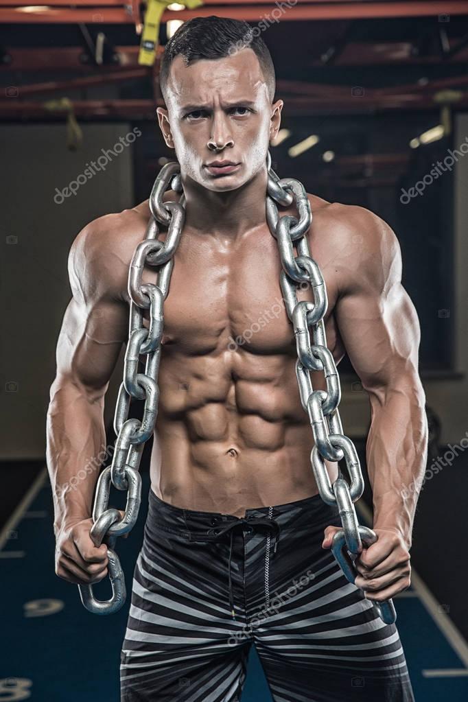 Hombre guapo con grandes músculos, posando en la cámara en el gimnasio 2024