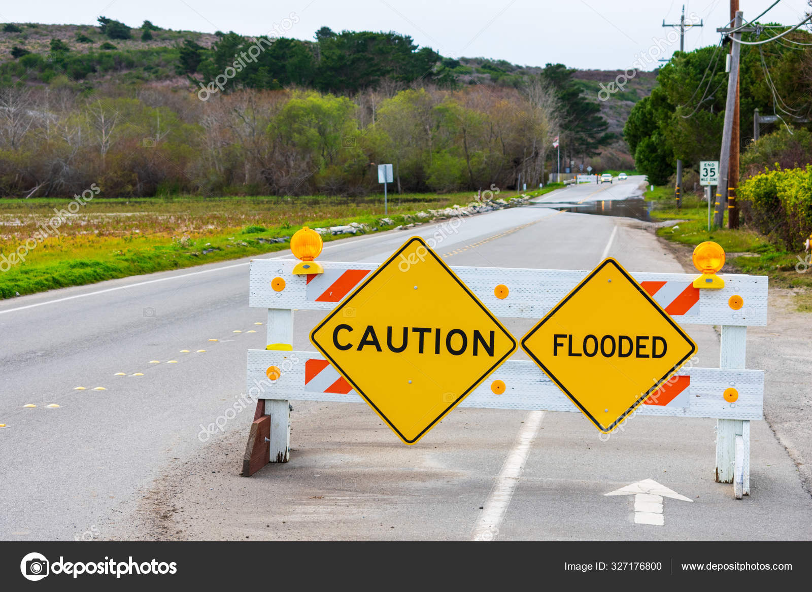 Caution and Flooded warning signs on barricade installed across two-way ...