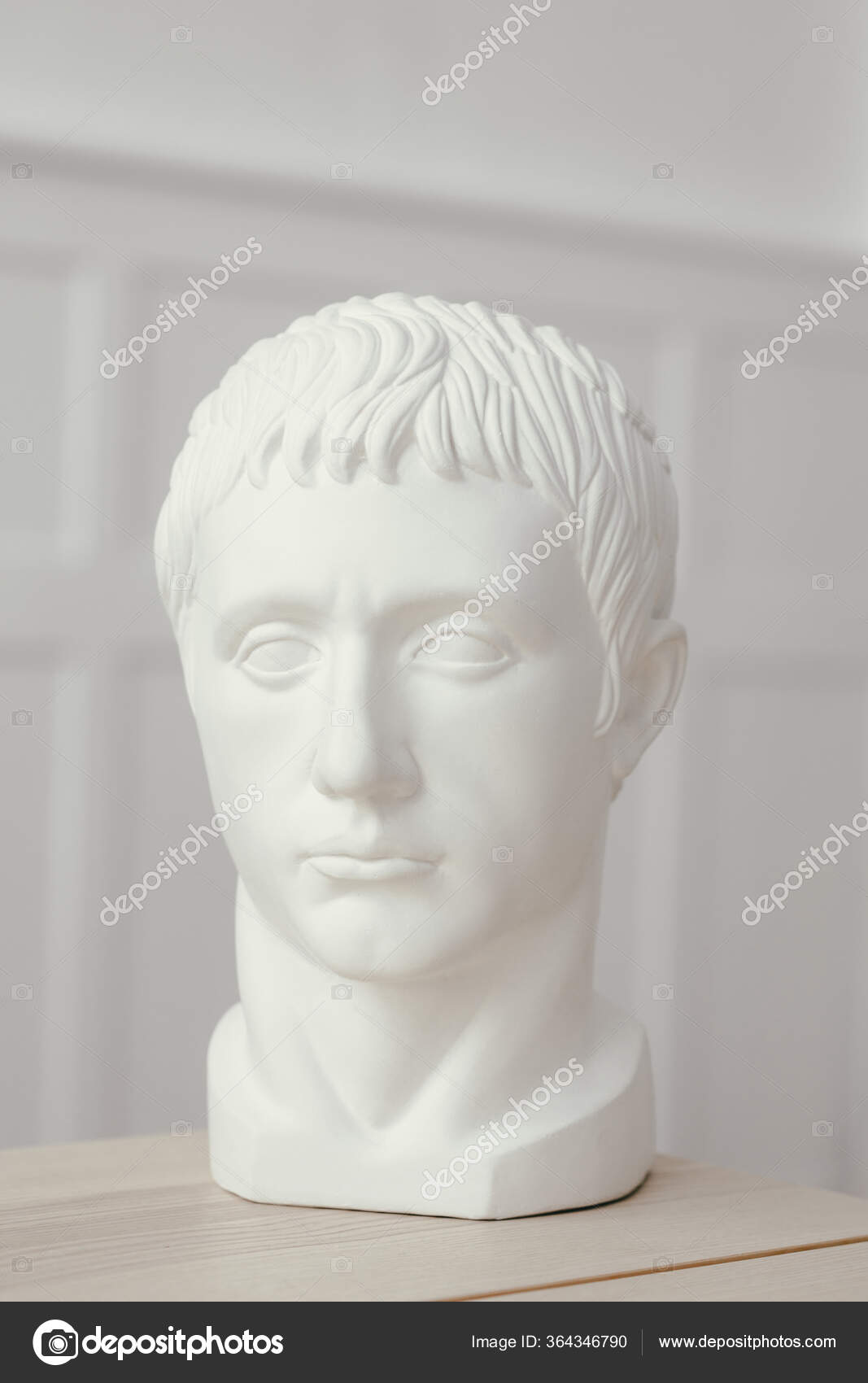 Plaster sculpture of Caesar's head stands on a wooden table in a ...