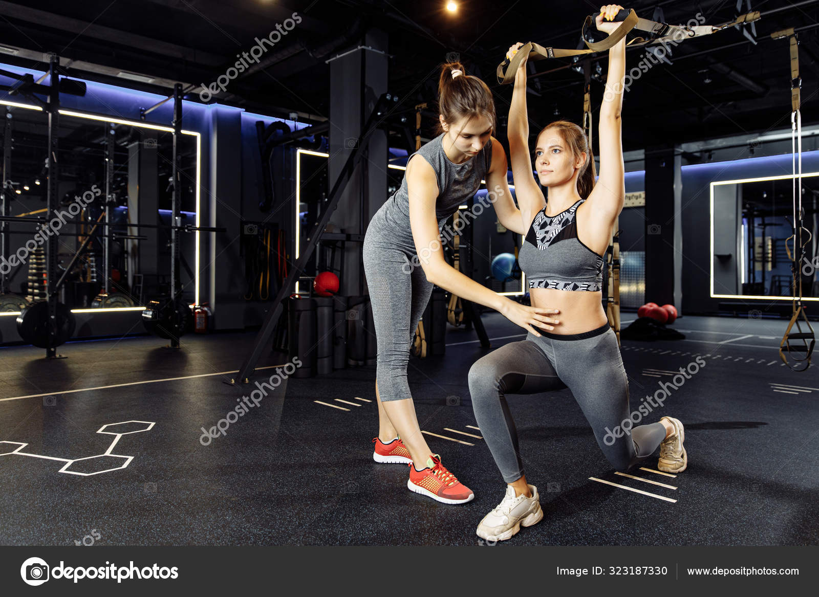 Young coach and sportive woman with arms raised train with elastic ...