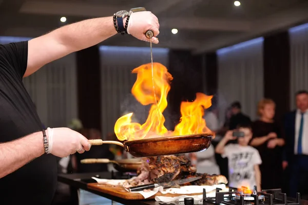 Chef, pouring alcohol into a frying pan with fire - Stock Image ...