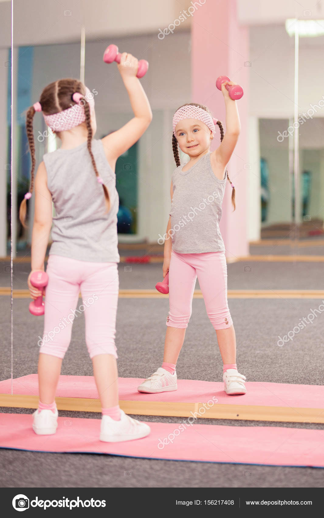 Girl child doing fitness exercises with dumbbells in health club ...