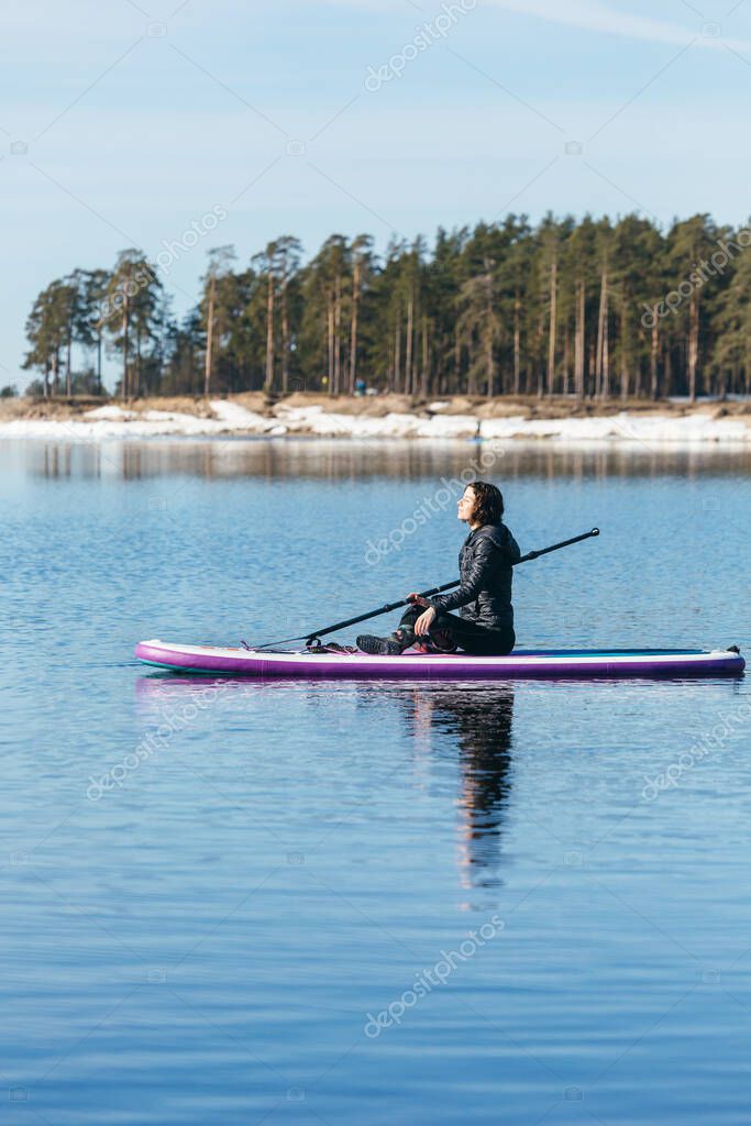 Mujer belleza calma sentarse en el tablero de SUP en el medio del lago ...