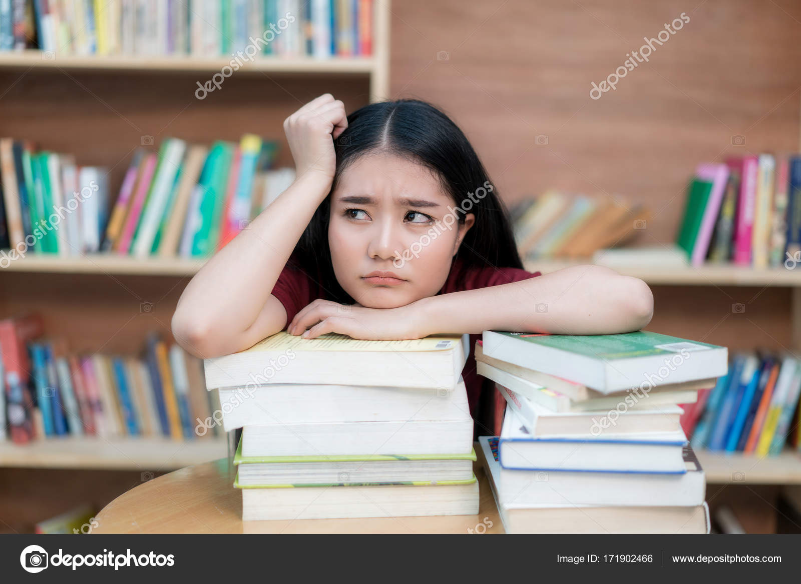 Asian woman student boring reading book at library with a lot of ...