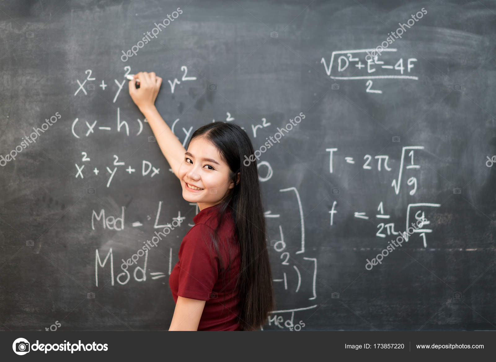 Beautiful Asian student writing on blackboard with chalk in clas ...