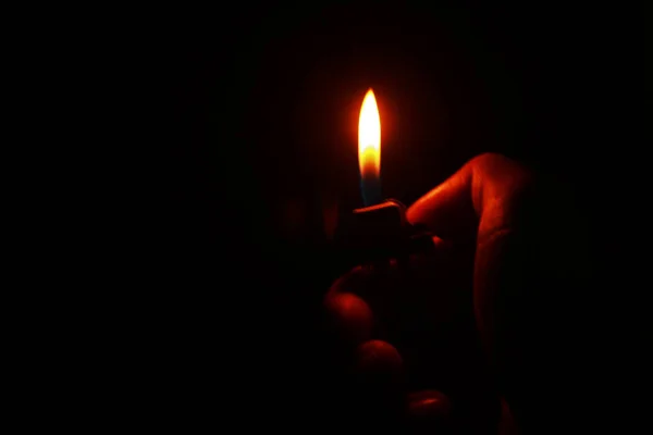 A lighter that gives light in the dark. Held by hand. in a dark place ...