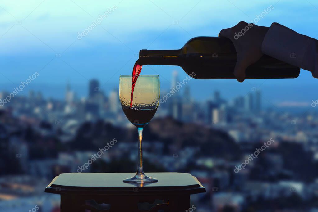 Mano femenina con copa de vino sobre fondo de ciudad de San Francisco ...