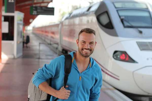 Handsome bearded man standing at railway station while waiting for his ...