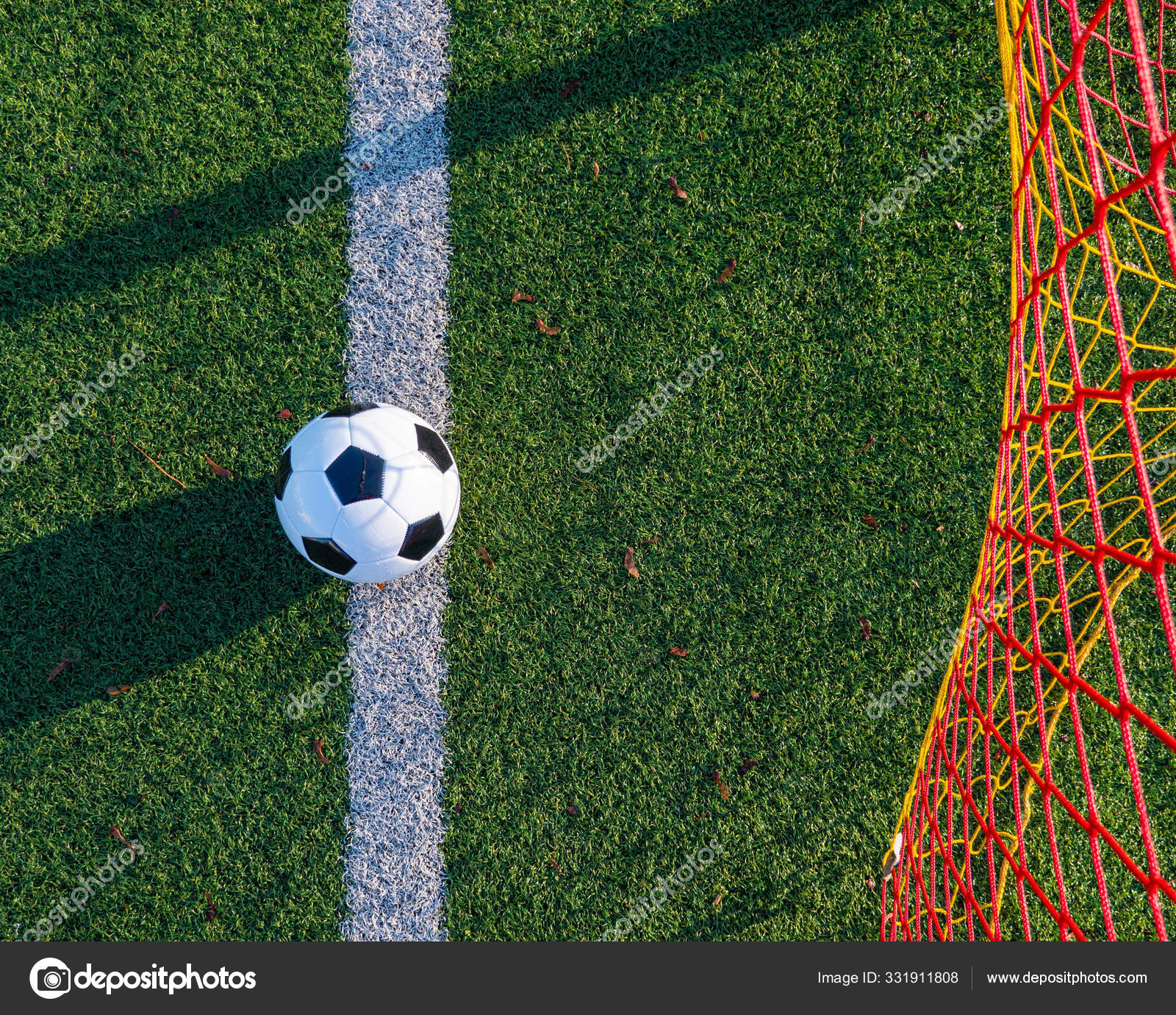 Shot from above on the ball behind the soccer goal line. Green grass ...