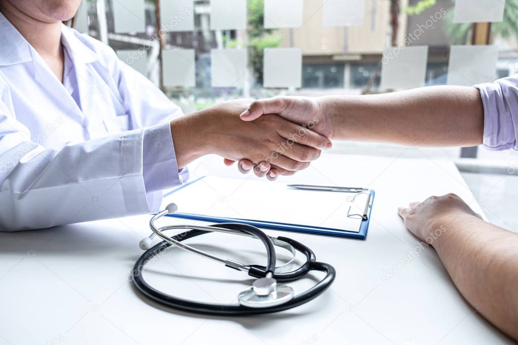 Médico y paciente estrechando las manos después de consultar con ...