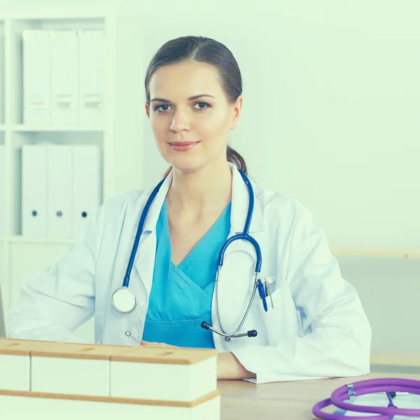 Beautiful young smiling female doctor sitting at the desk and writing ... Beautiful young smiling female doctor sitting at the desk and writing ...