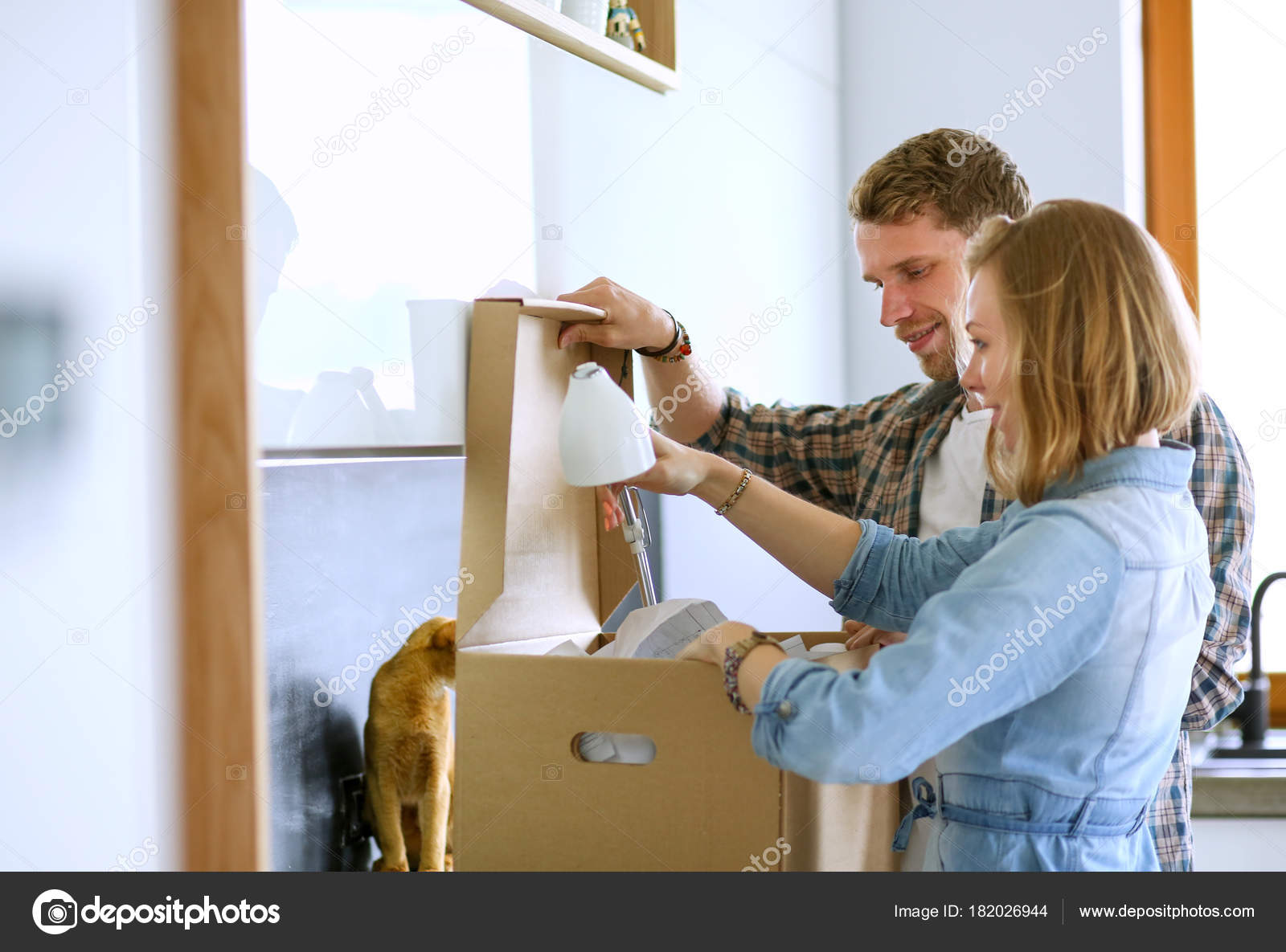 Young Couple Carrying Big Cardboard Box At New Home Moving House Young