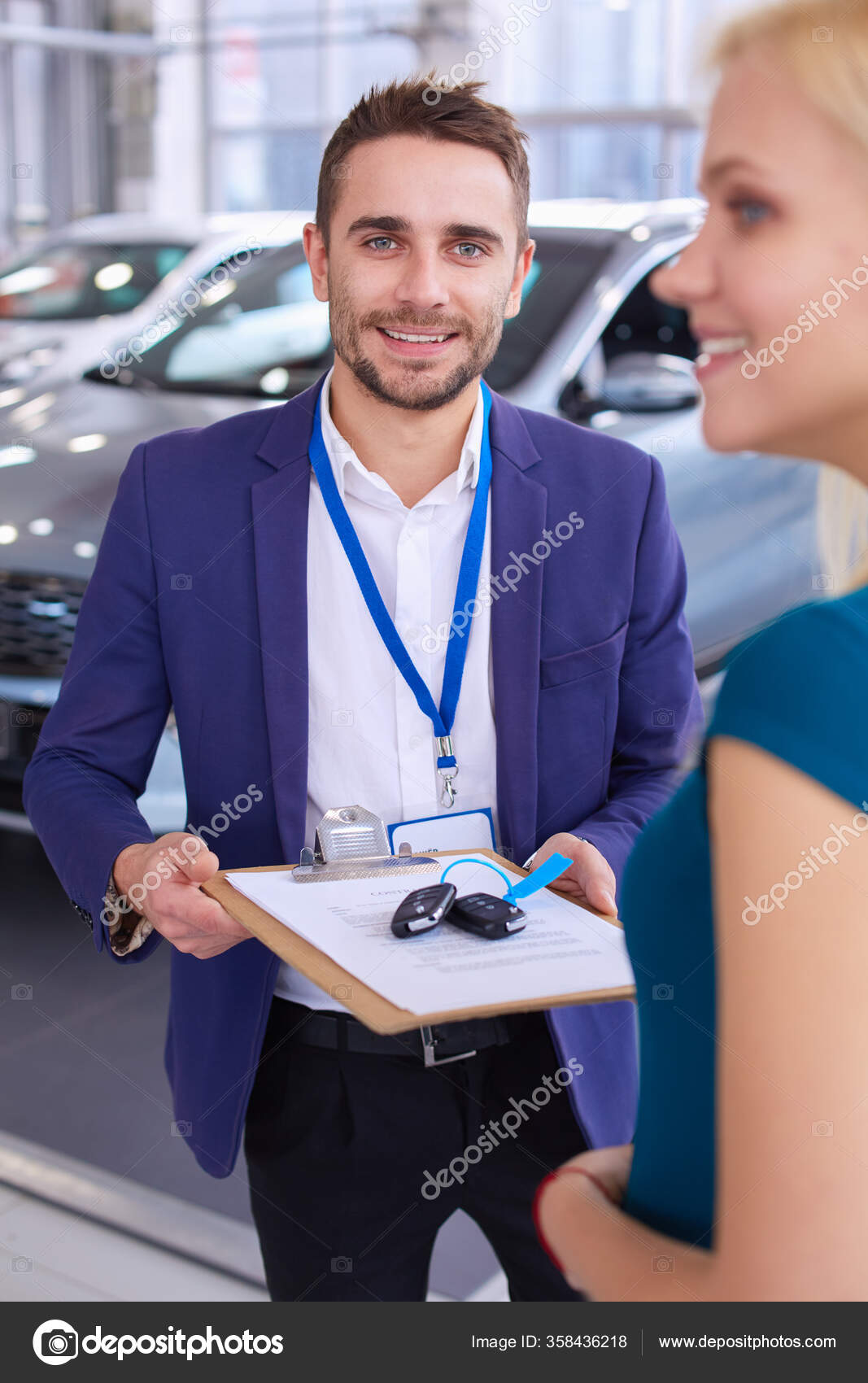 Car salesman sells a car to happy customer in car dealership and hands ...