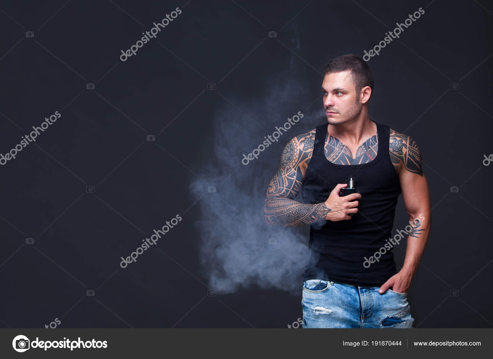 Vaper. The man with a muscular torso with tattoos smoke an electronic ...