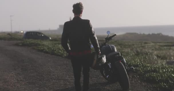 Back view of man getting on motorcycle by the seafront — Stock Video ...