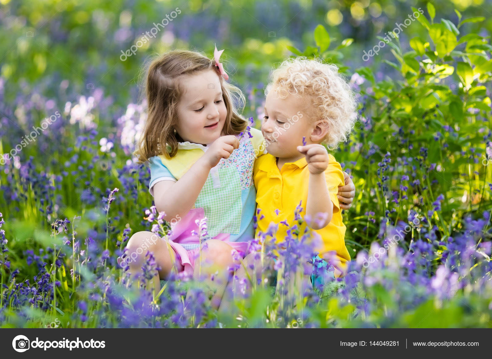 Niños jugando en el jardín floreciente con flores de Bluebell ...