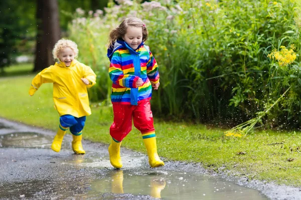 Kids play in rain and puddle in autumn Stock Photo by ©FamVeldman 151866772